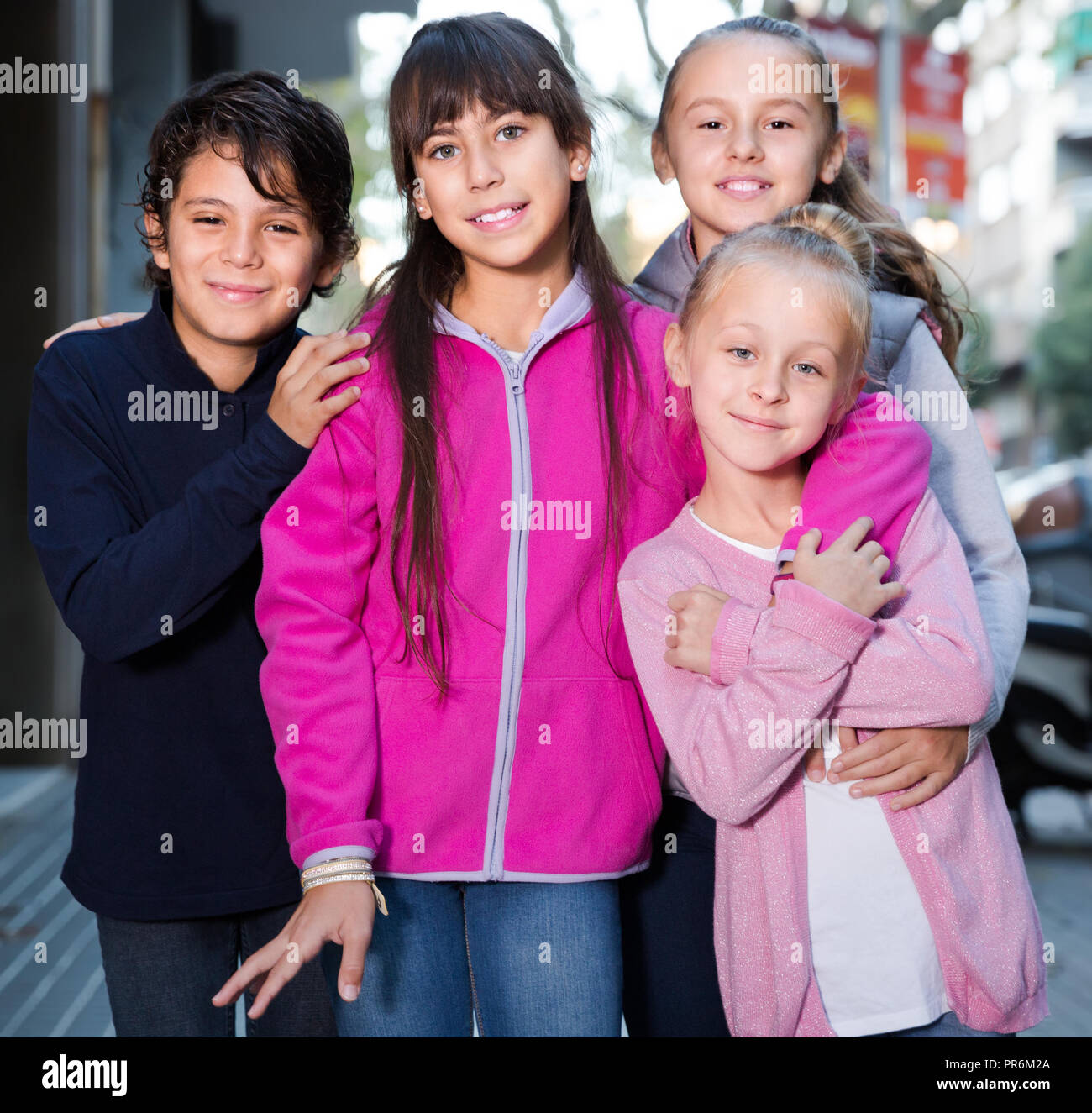 four happy children play without parents in street on sidewalk in ...