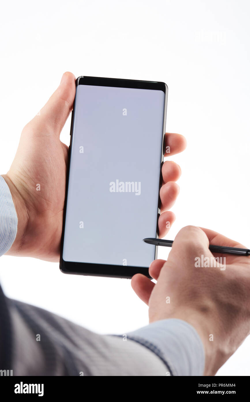 Holding modern smartphone with stylus in hands isolated on white ...