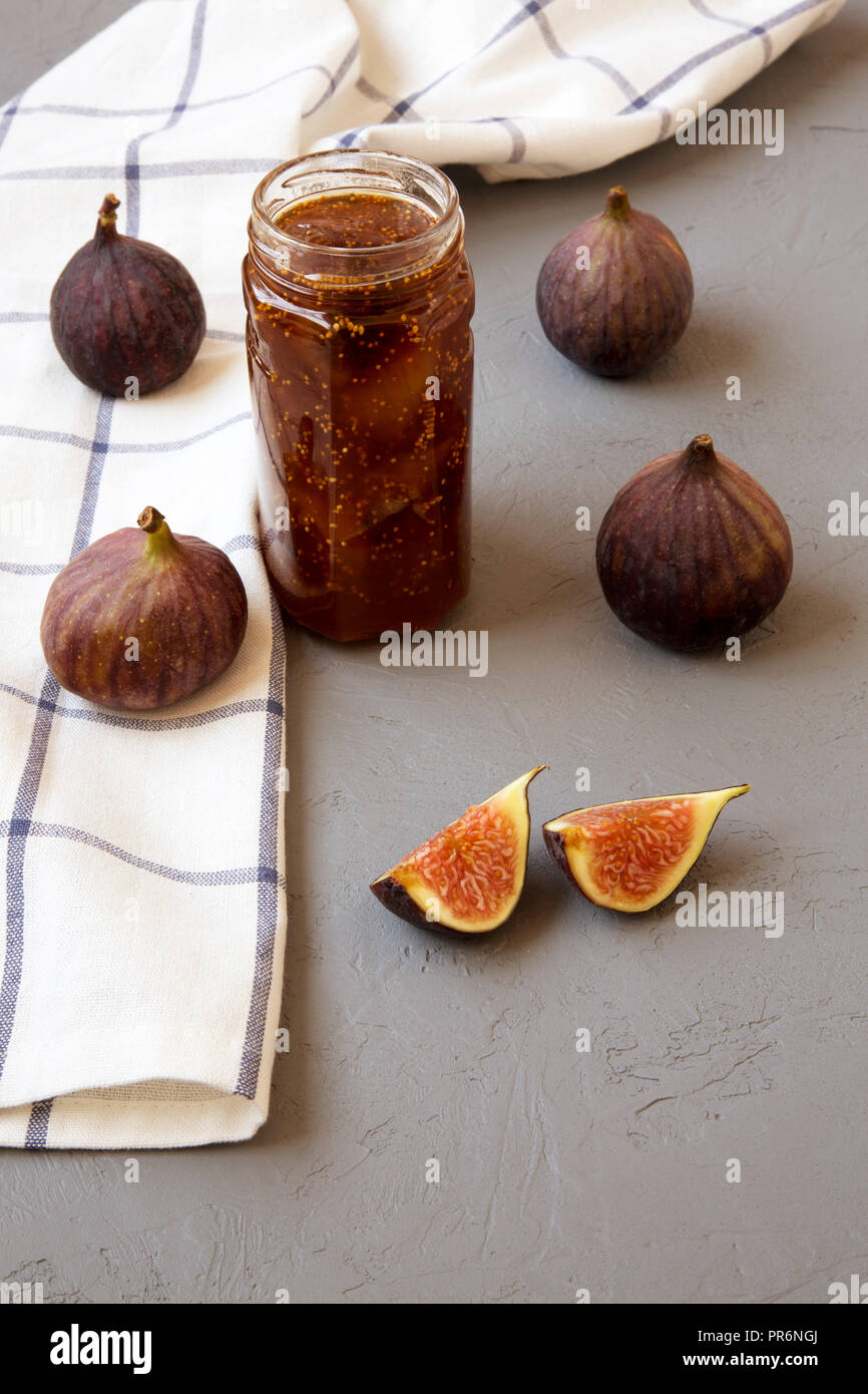 Fig jam in glass jar and fresh figs on grey background, side view ...