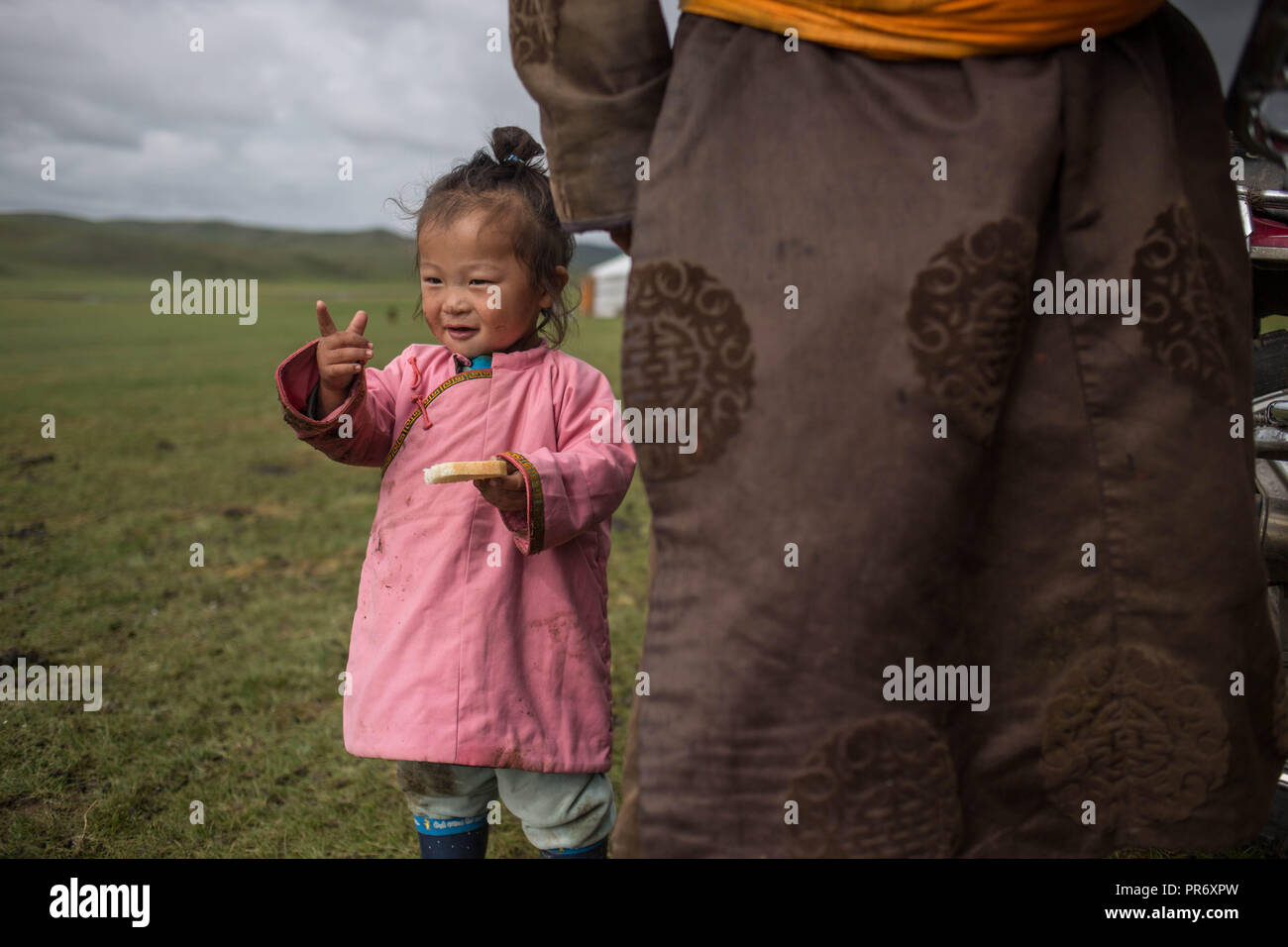 A little girl wearing a traditional deel seen pointing at the horizon outside her home near the ...