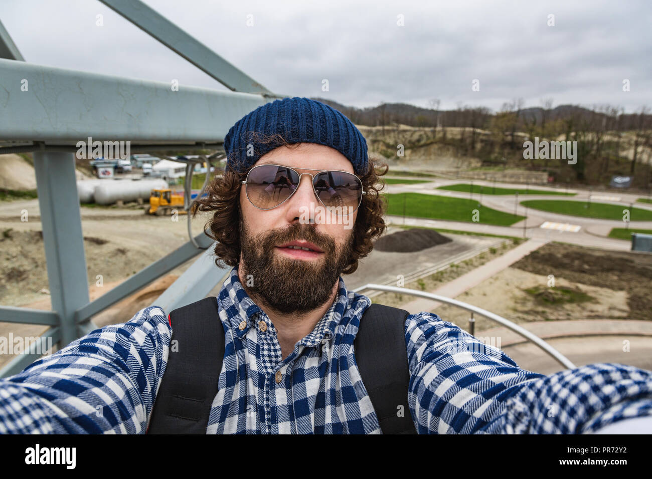man makes selfies. Vlogging concept. Hipster, tourist with tousled hair ...