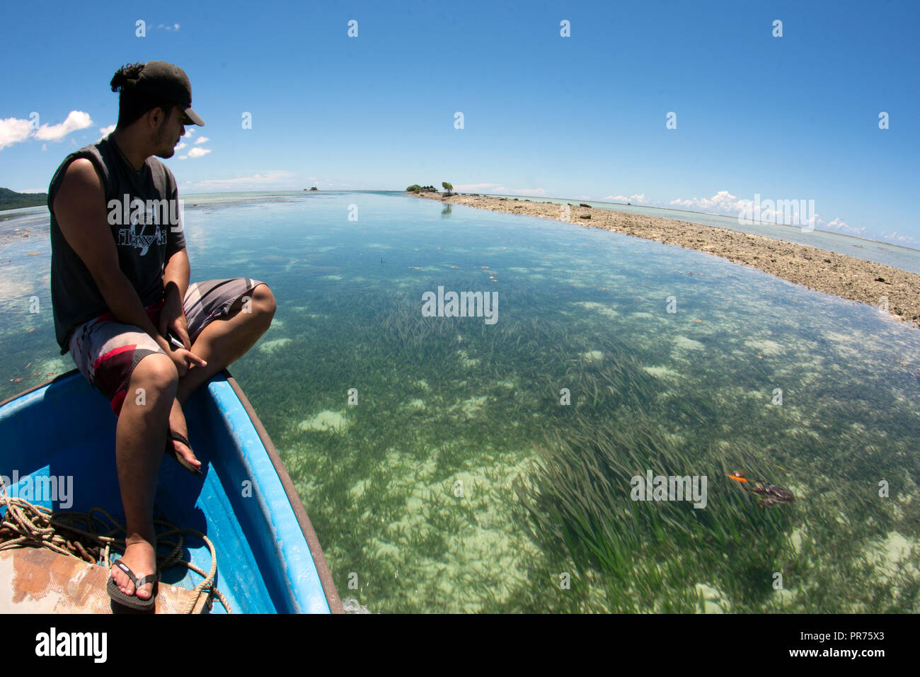 Micronesian man on a boat ride over a seagrass bed in the lagoon of ...