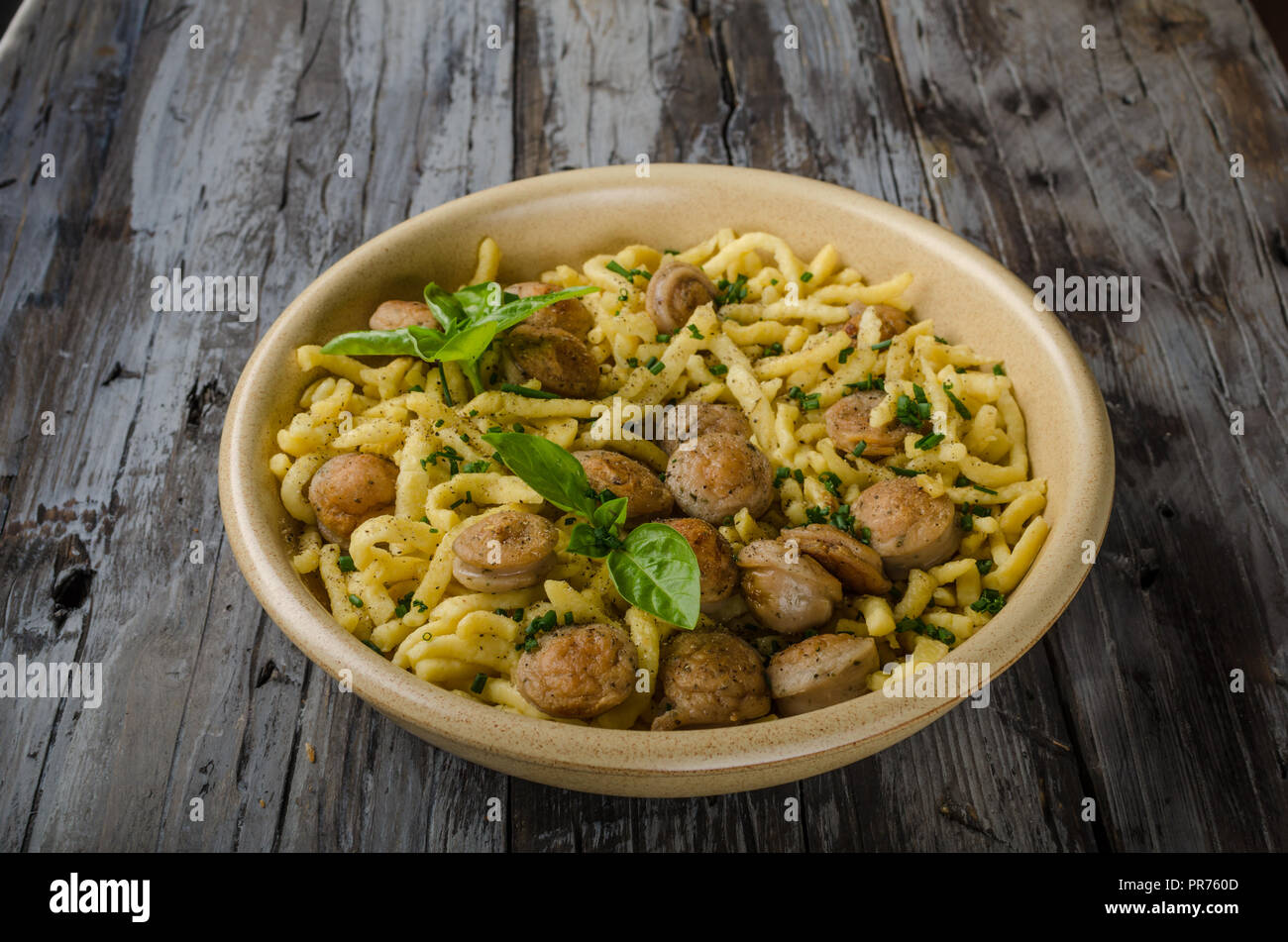 Homemade spaetzle, barbecue sausage and fresh cheese, herbs on rustic ...