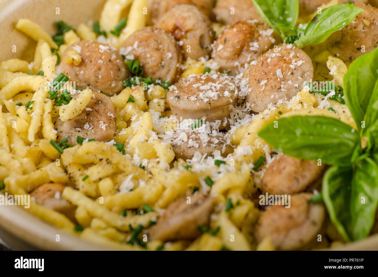 Homemade spaetzle, barbecue sausage and fresh cheese, herbs on rustic ...