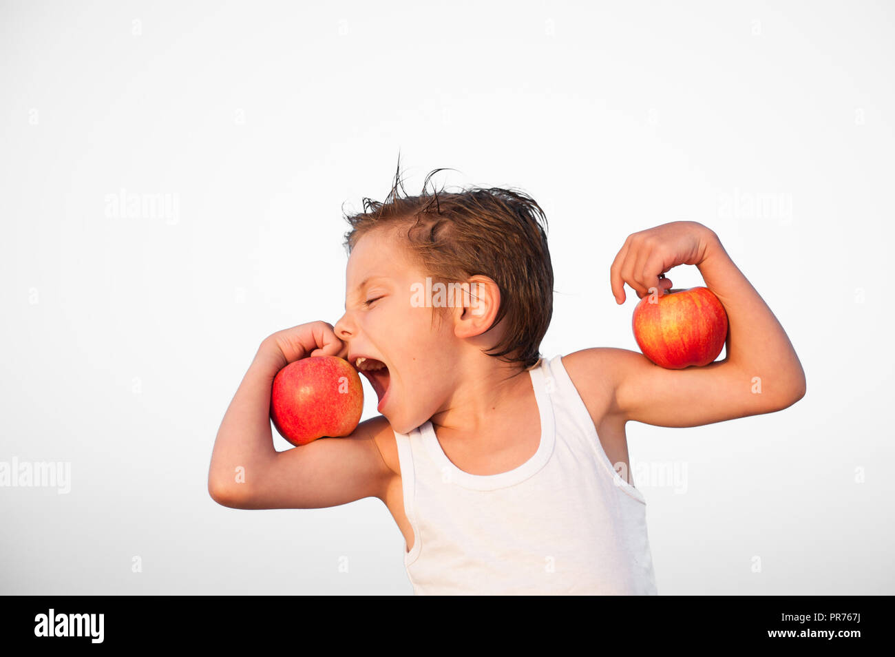 healthy caucasian kid biting eat red apple on his biceps muscle on ...