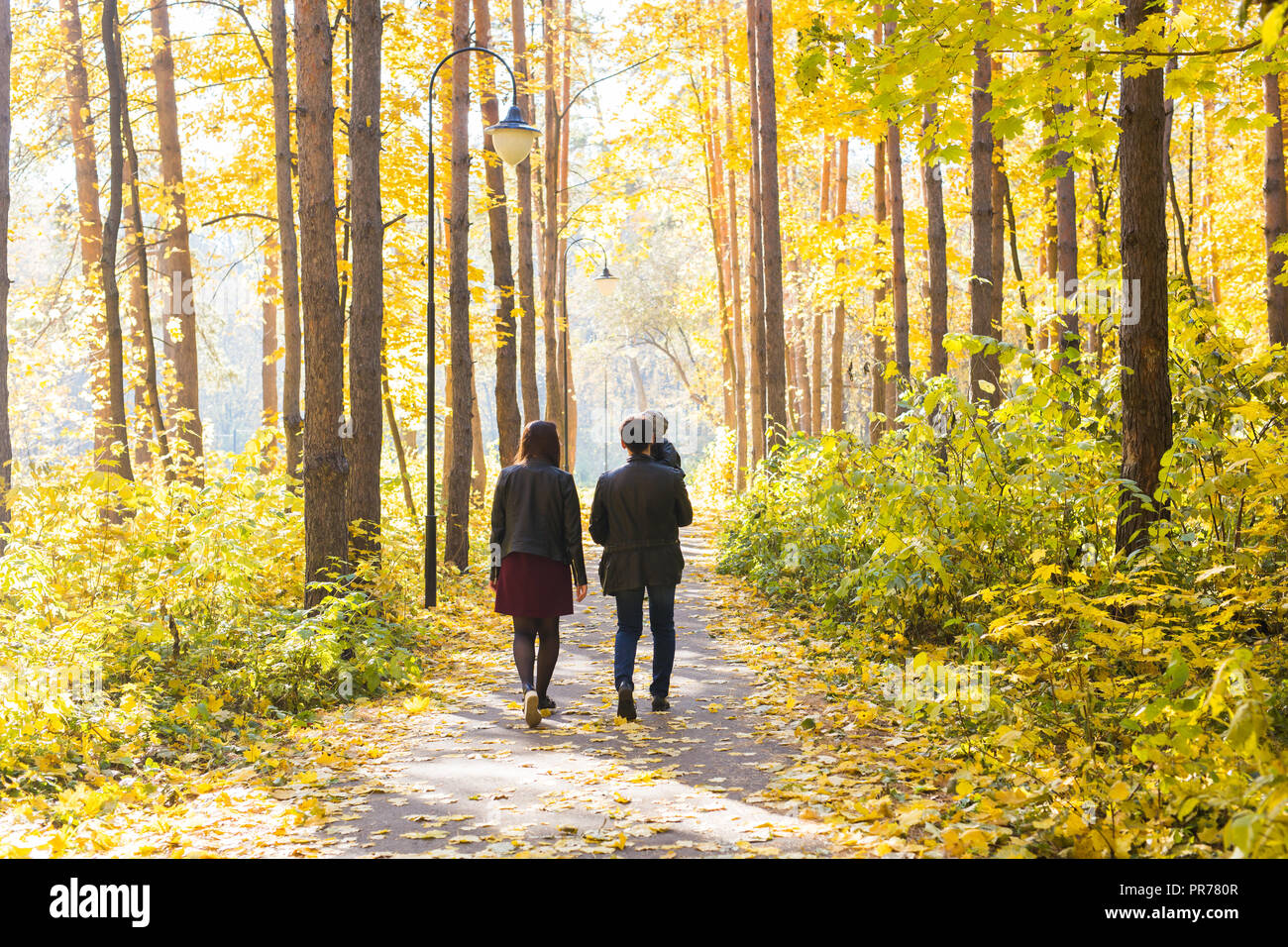 Fall, nature and family concept - family walking in autumn park, back ...