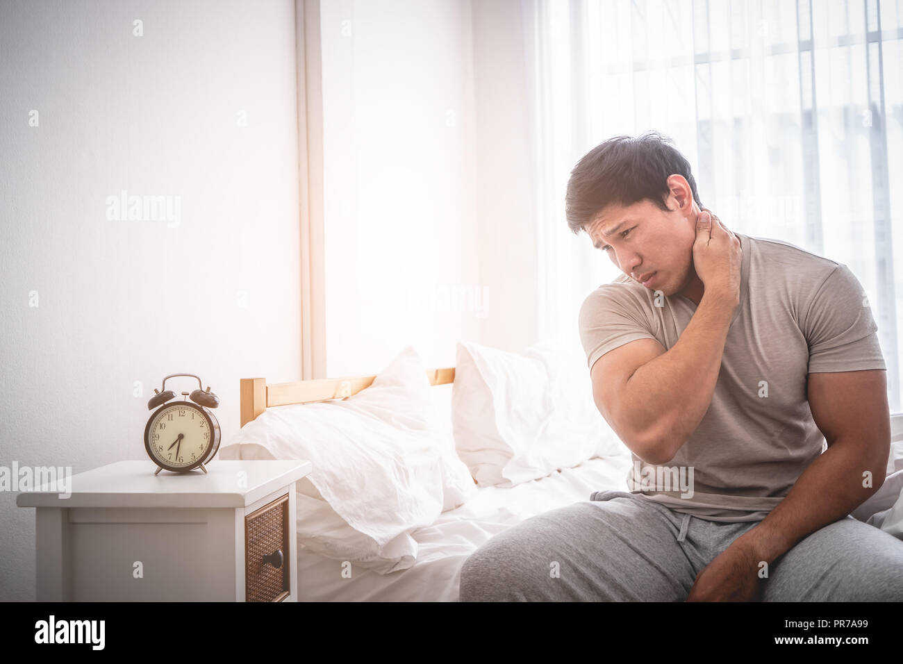 Male woke up by alarm clock having neck pain from sleeping Stock Photo ...