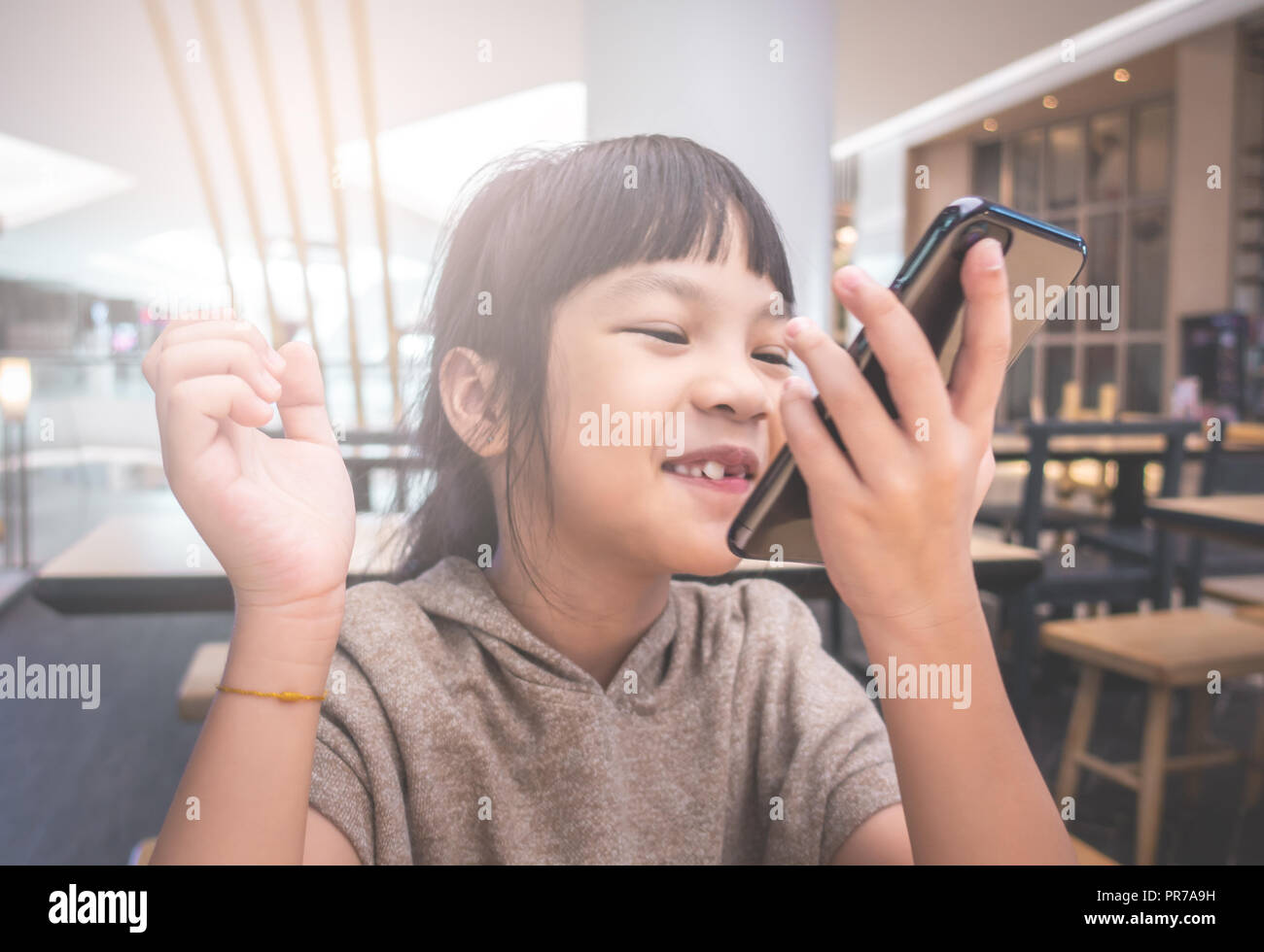 Asian kid is talking on speaker phone in cafe Stock Photo - Alamy