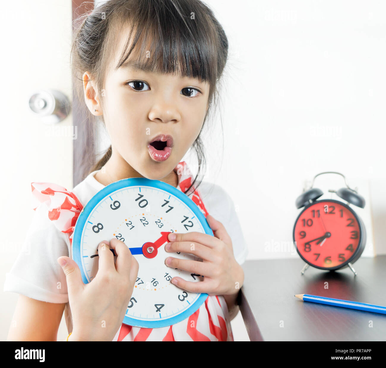 Little asian girl holding toy clock for school time Stock Photo - Alamy