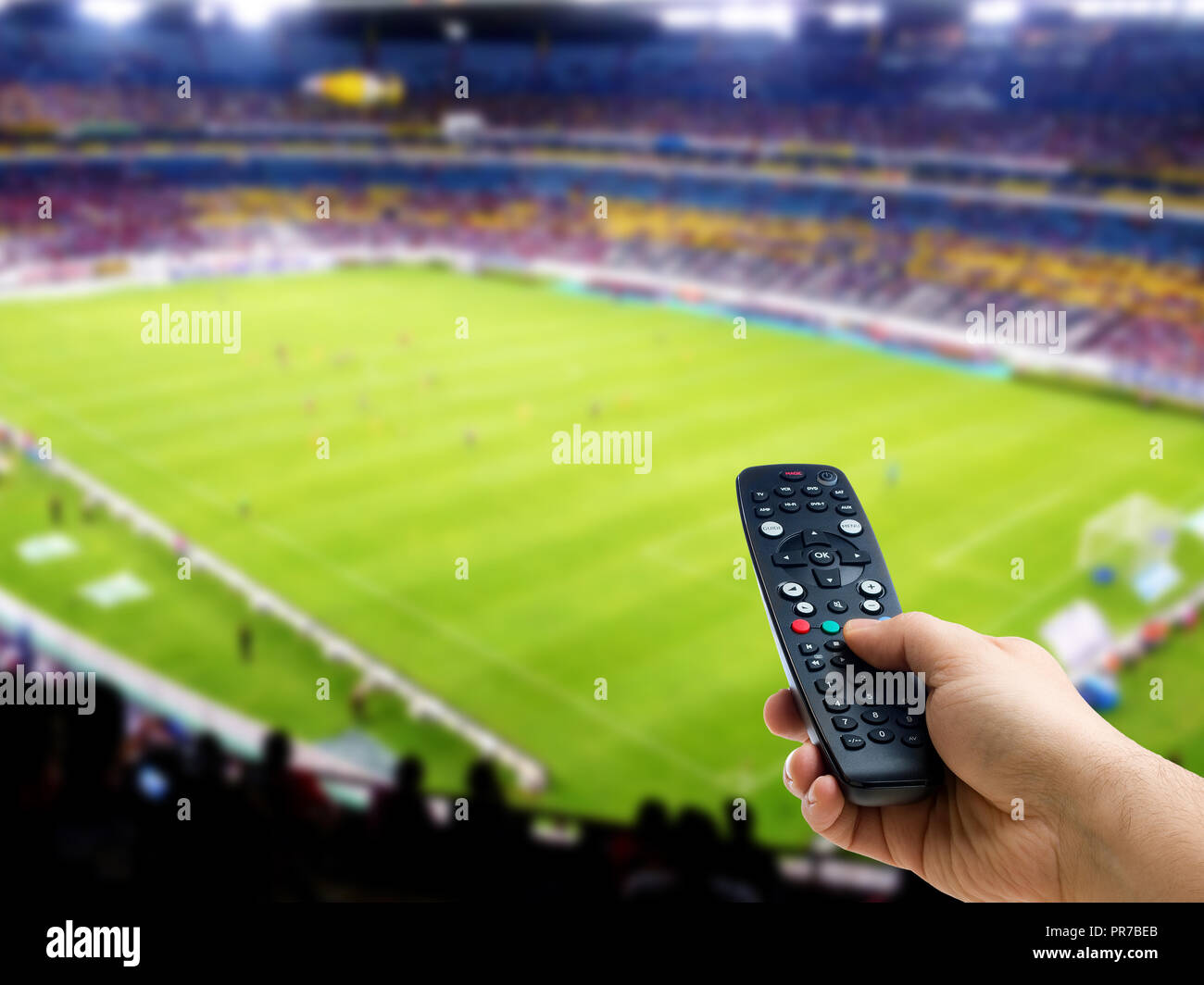 Hand holding remote control on soccer or football match TV or ...
