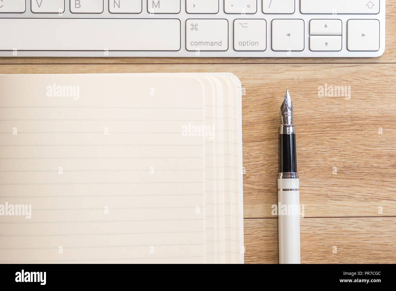 Office table with notepad, keyboard and fountain pen. View from above ...