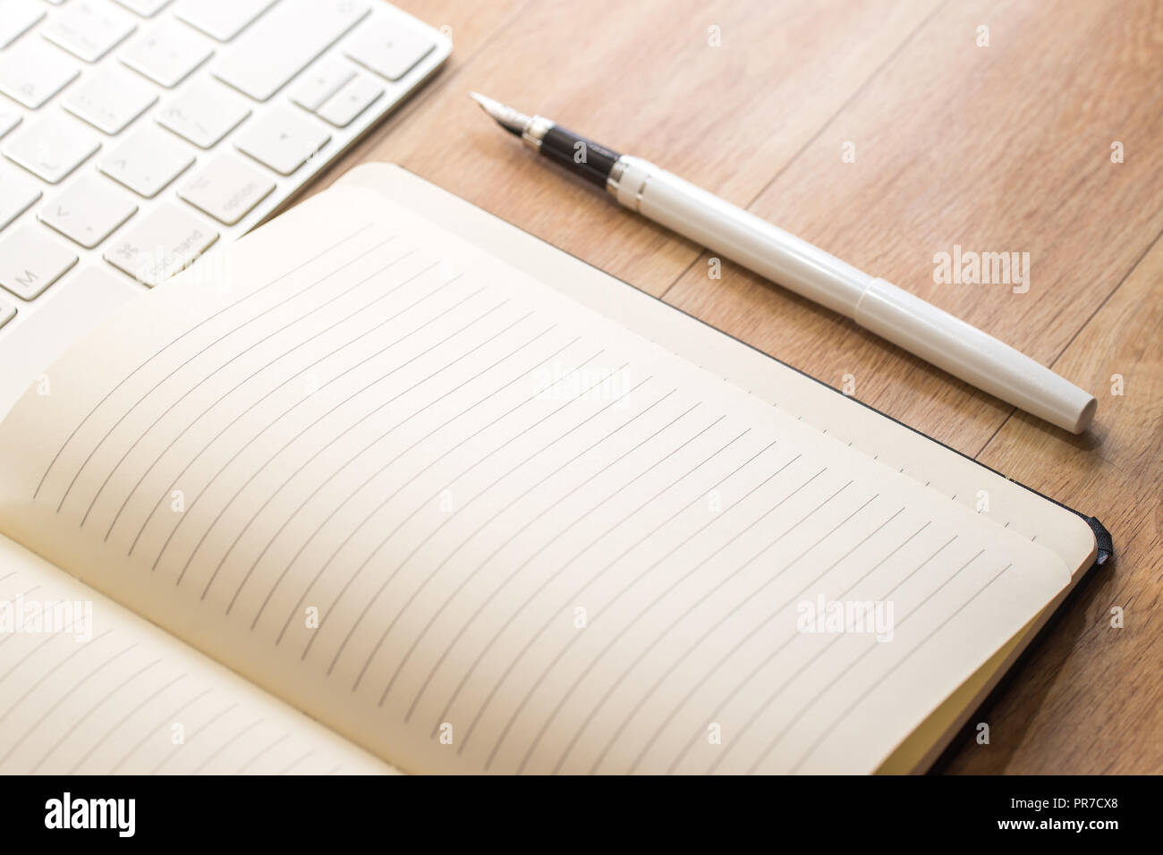 Office table with notepad, keyboard and fountain pen. View from above ...