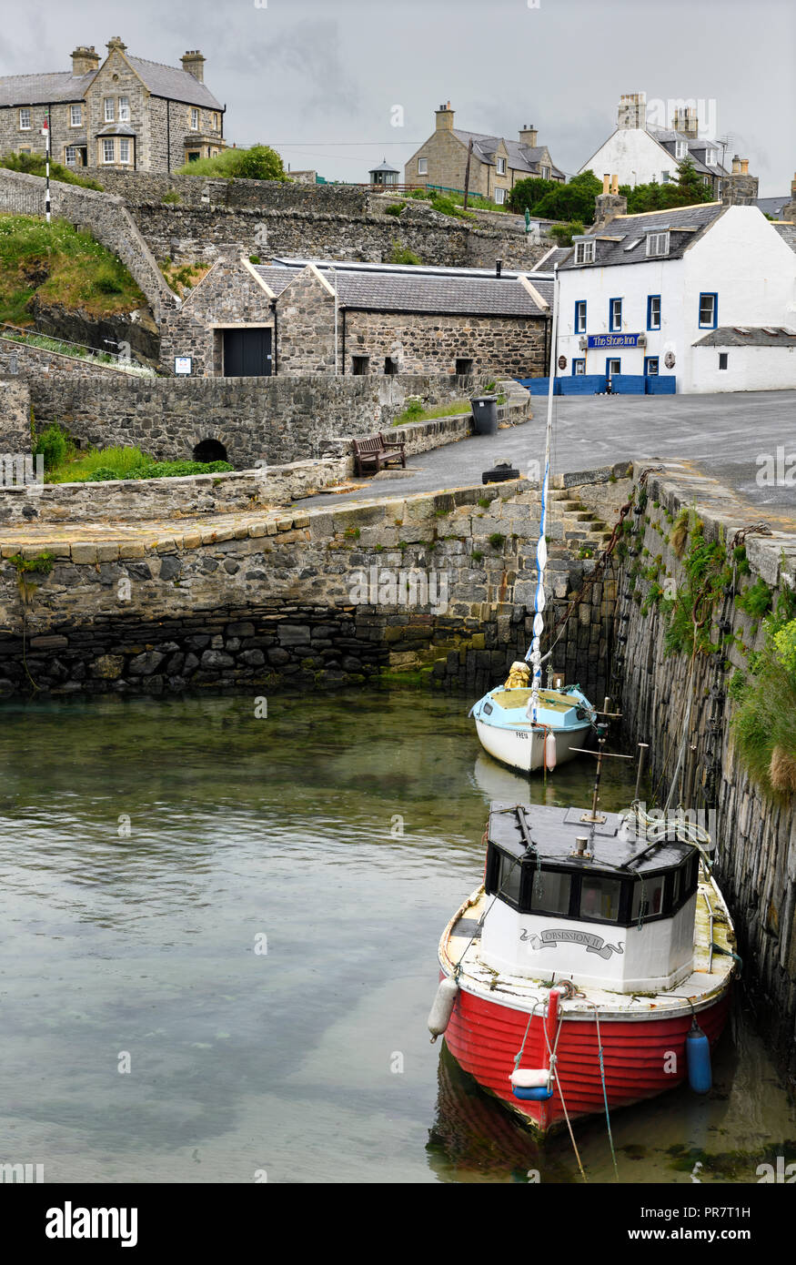 Moored boats and the Shore Inn at the Old Harbour with stone buildings ...