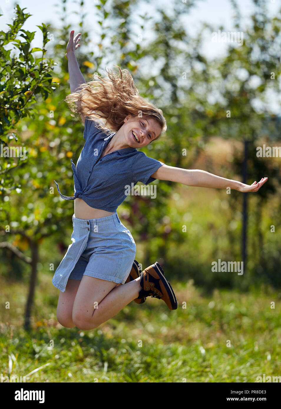 Young farmer woman jumping for joy in her orchard Stock Photo - Alamy