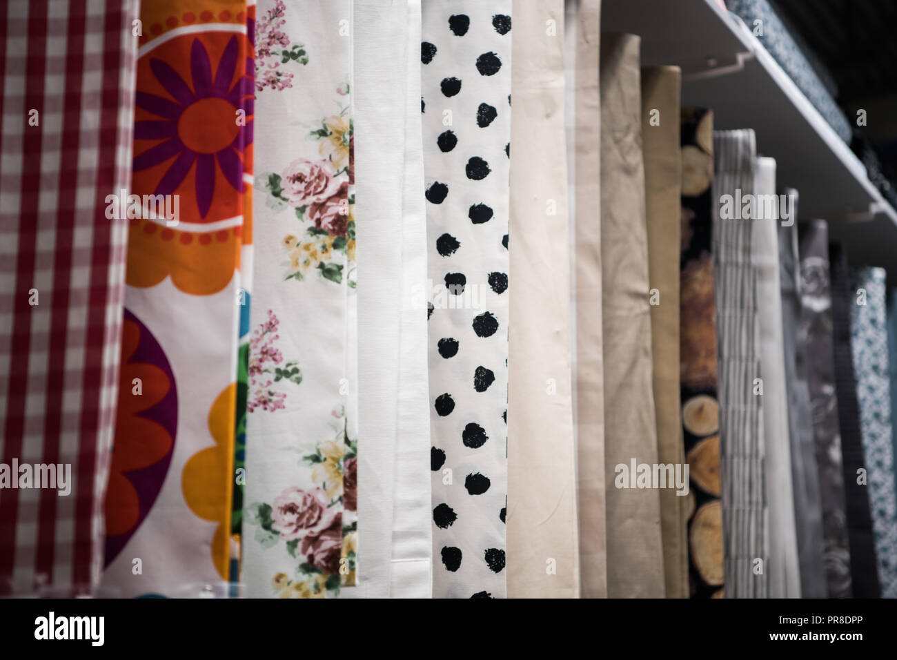 Colorful curtain samples hanging from hangers on rail in a display ...