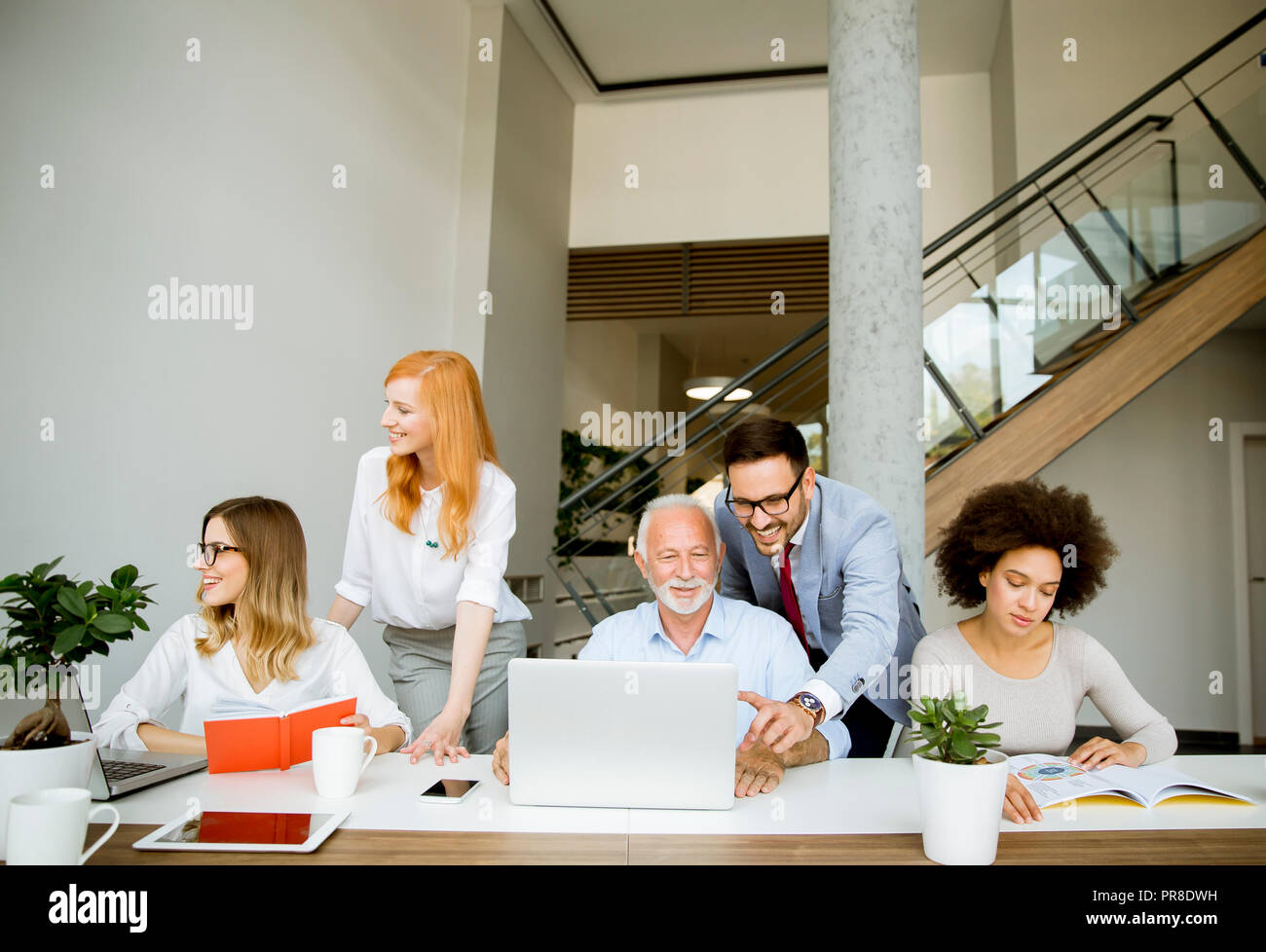 View at group of young multiracial business people around table during ...