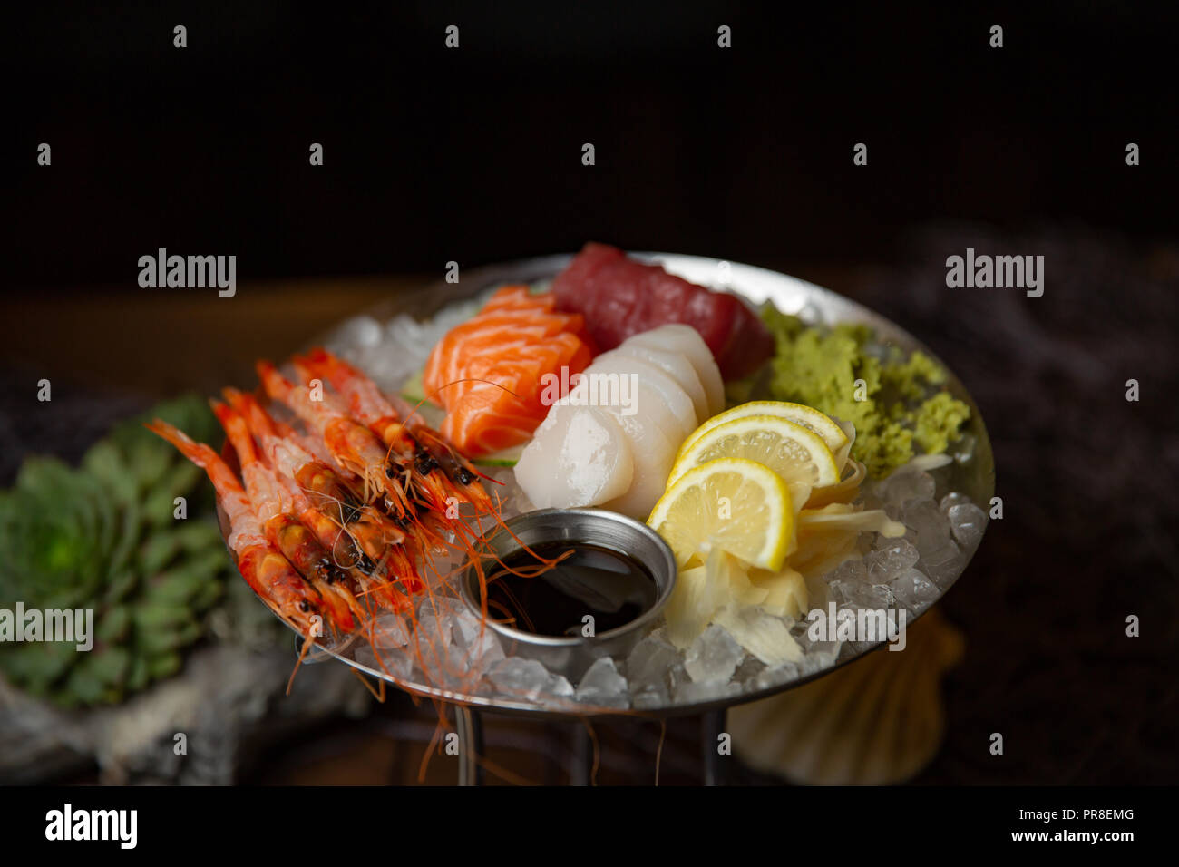 Mixed sliced fish sashimi and shrimps on ice in black bowl. Sashimi ...