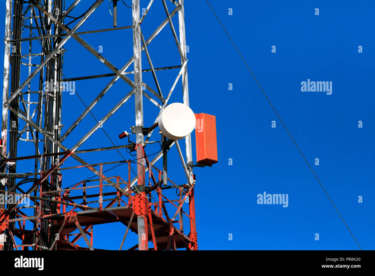 Red and white communications tower with some equipment Stock Photo - Alamy