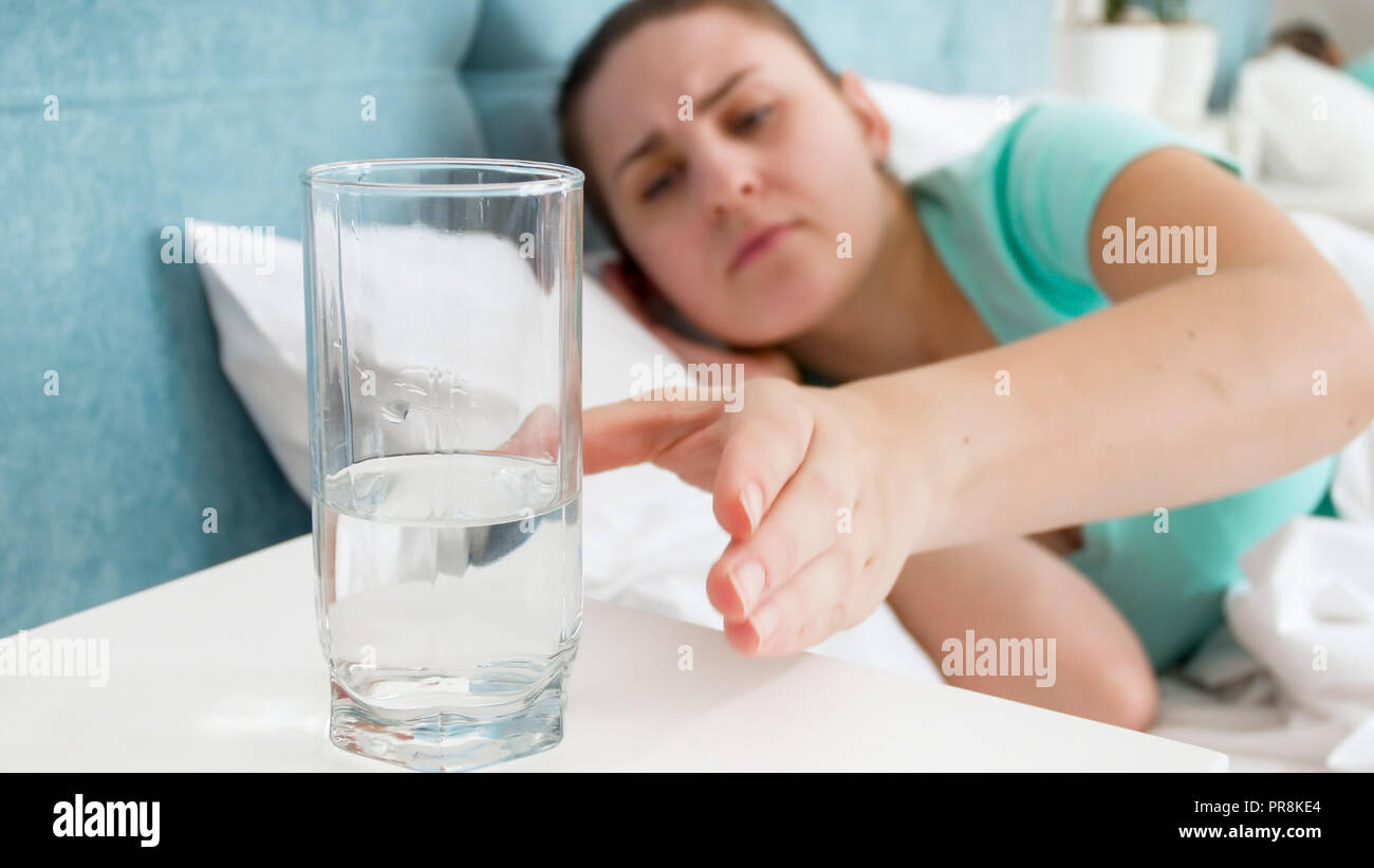 Portrait of sick woman taking glass of water from bedside table Stock ...