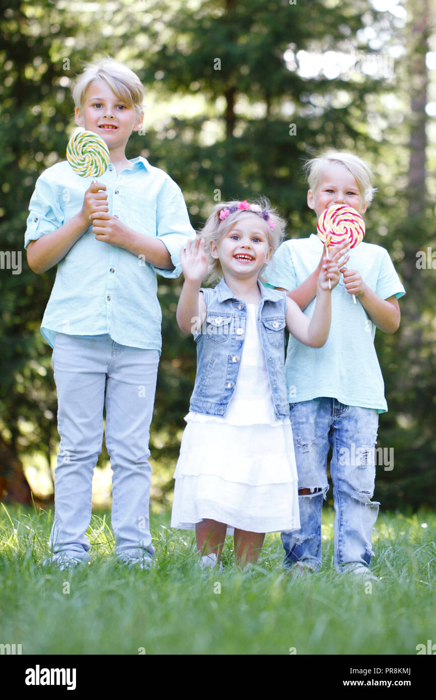 Group of happy children eating lollipops outdoors in summer park Stock ...