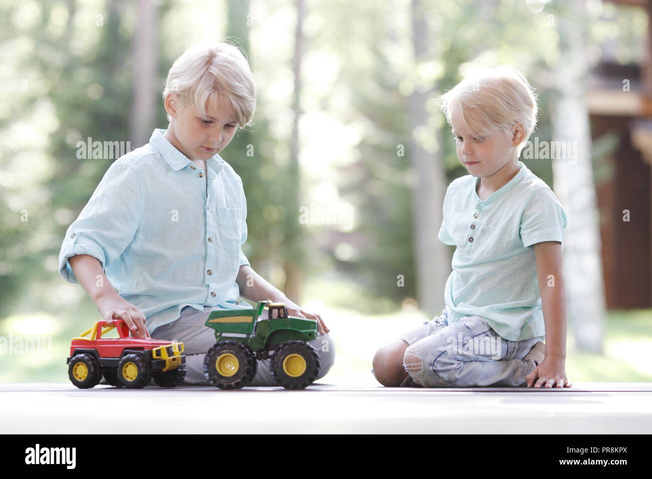 Little brothers playing with toy cars outdoors Stock Photo - Alamy