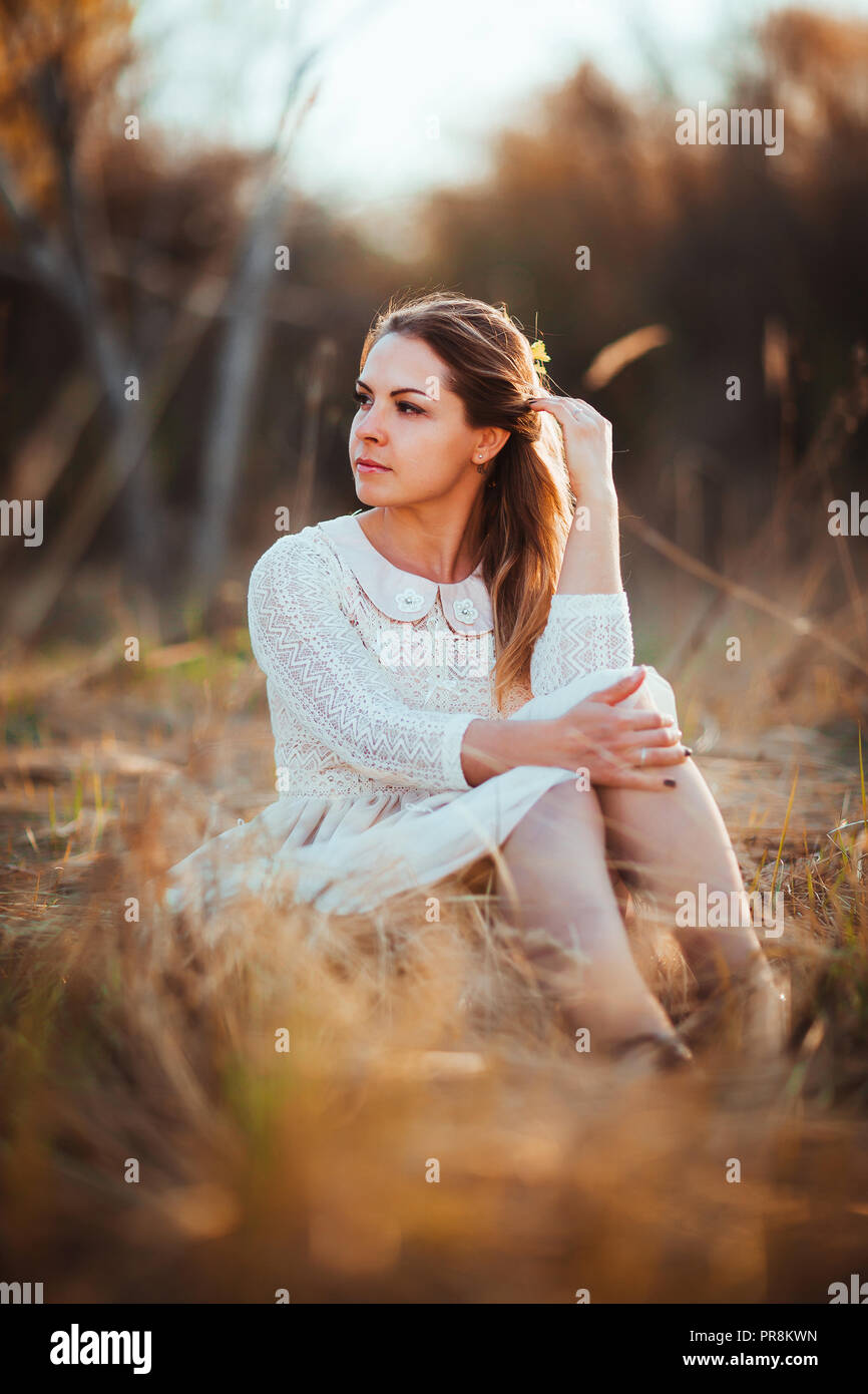 girl is sitting in the field on the sunset background Stock Photo - Alamy