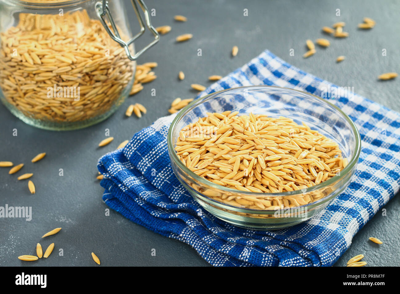 Raw grain of oats in a glass bowl on a gray table Stock Photo - Alamy