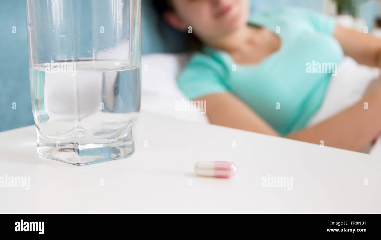 Closeup image of pill and glass of water on bedside table Stock Photo ...