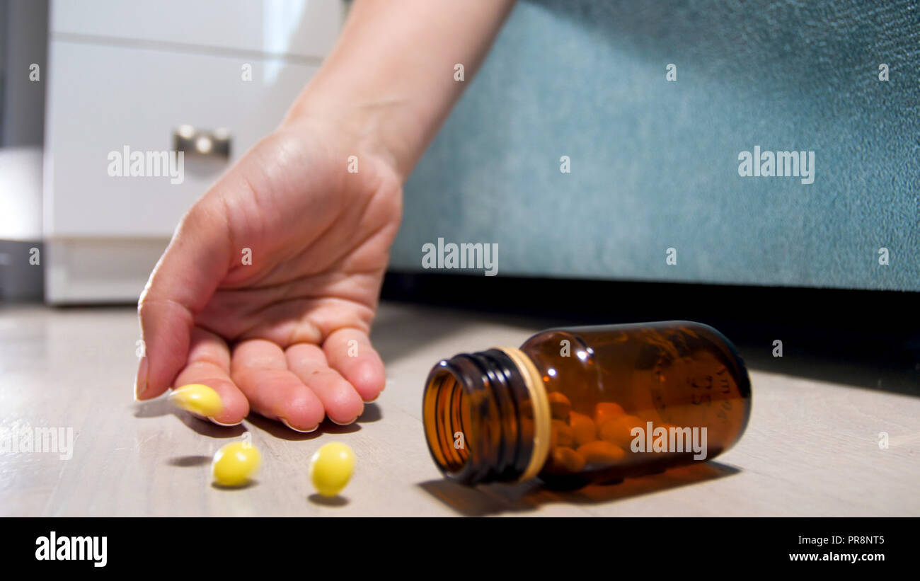 Closeup photo of bottle of pills falling from female hand lying on ...