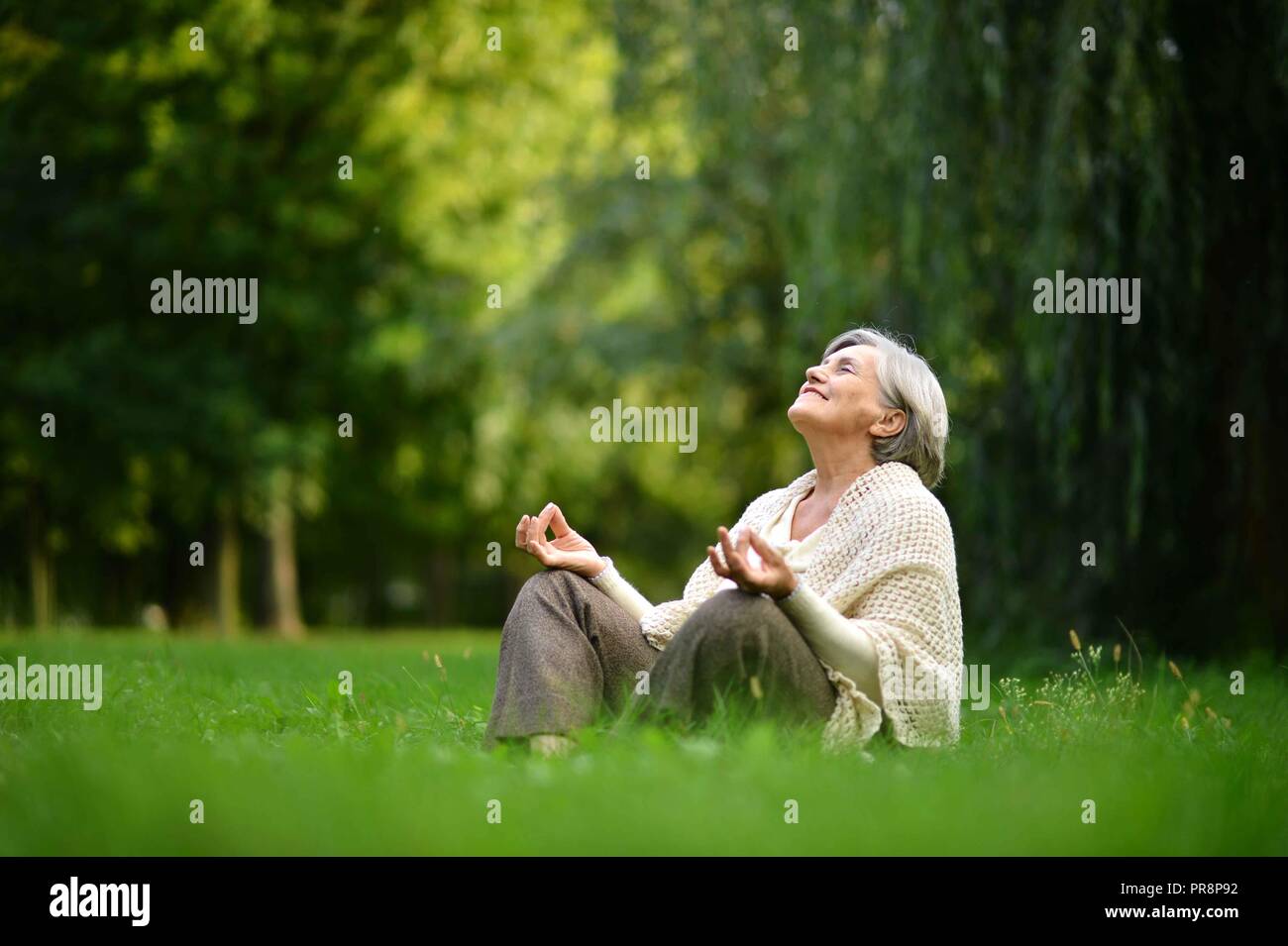 Elderly woman meditating in the summer park Stock Photo - Alamy