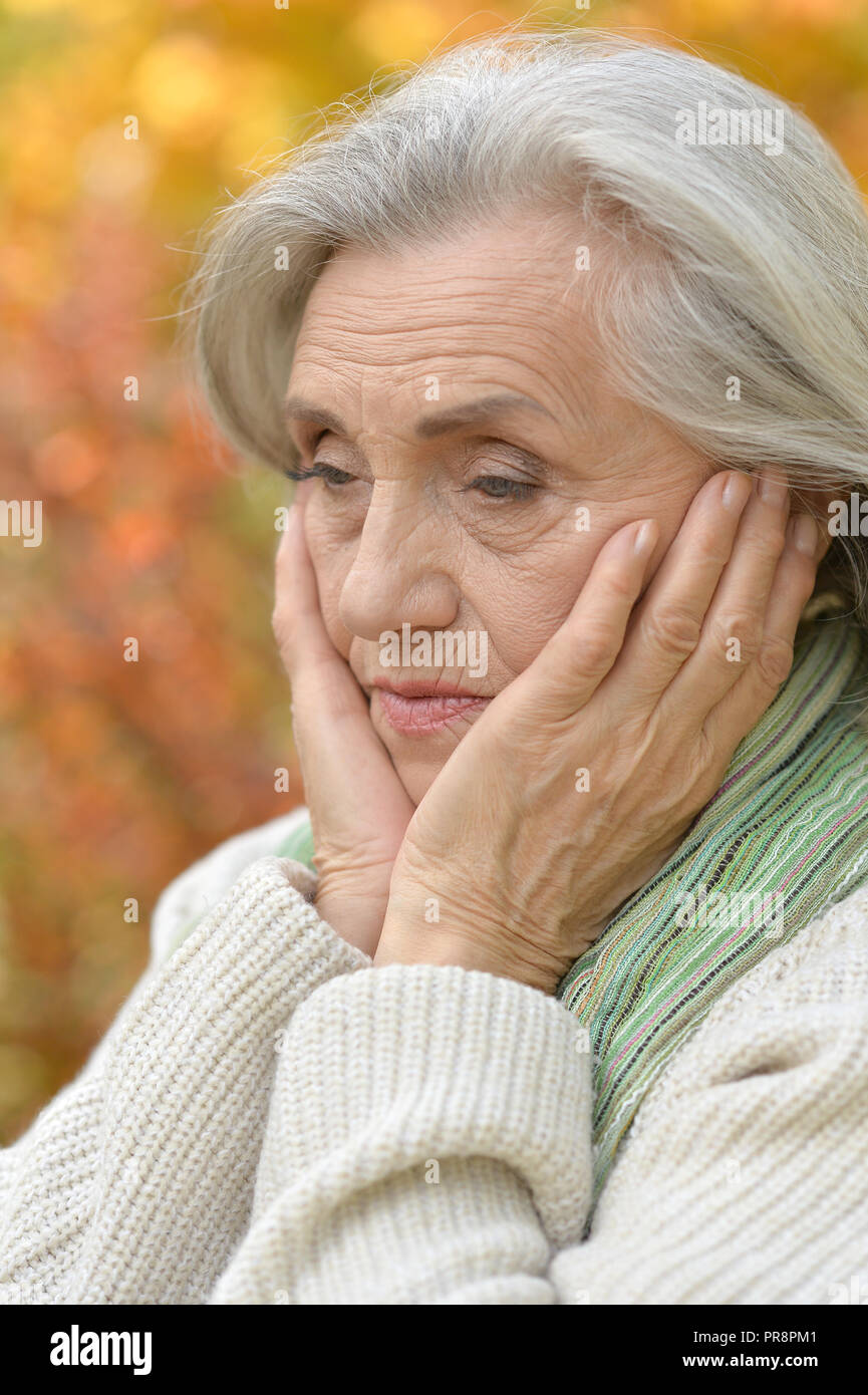 Portrait of sad senior woman in autumn park Stock Photo - Alamy