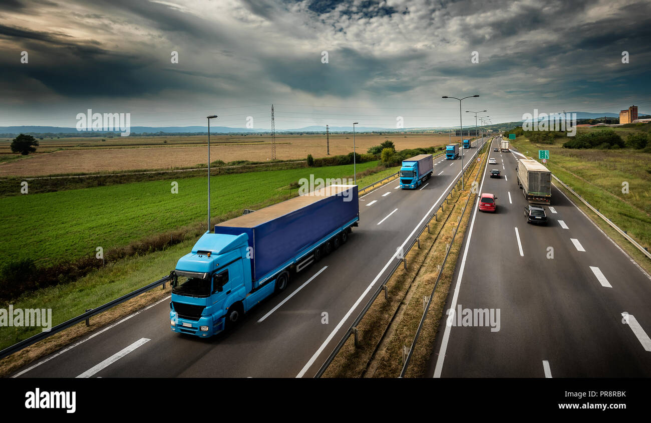 Caravan or convoy of Blue Lorry trucks in line on a country highway ...