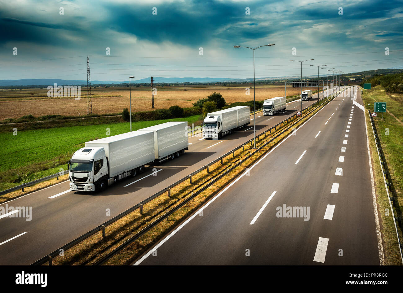 Caravan or convoy of White Lorry trucks in line on a country highway ...