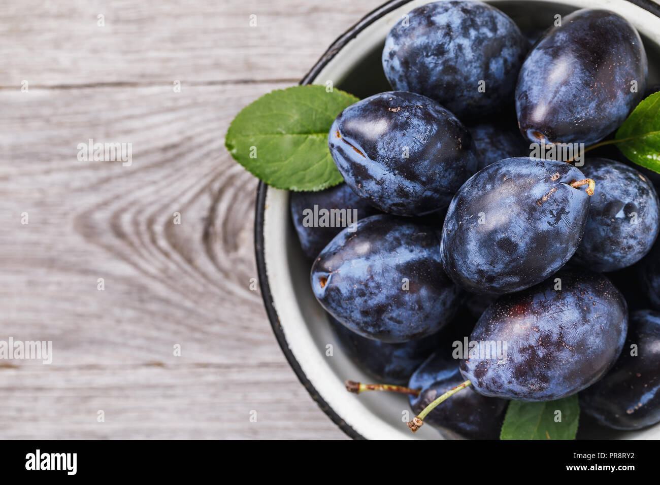 Full plate of ripe prune fruits on wooden table with copy space, top ...