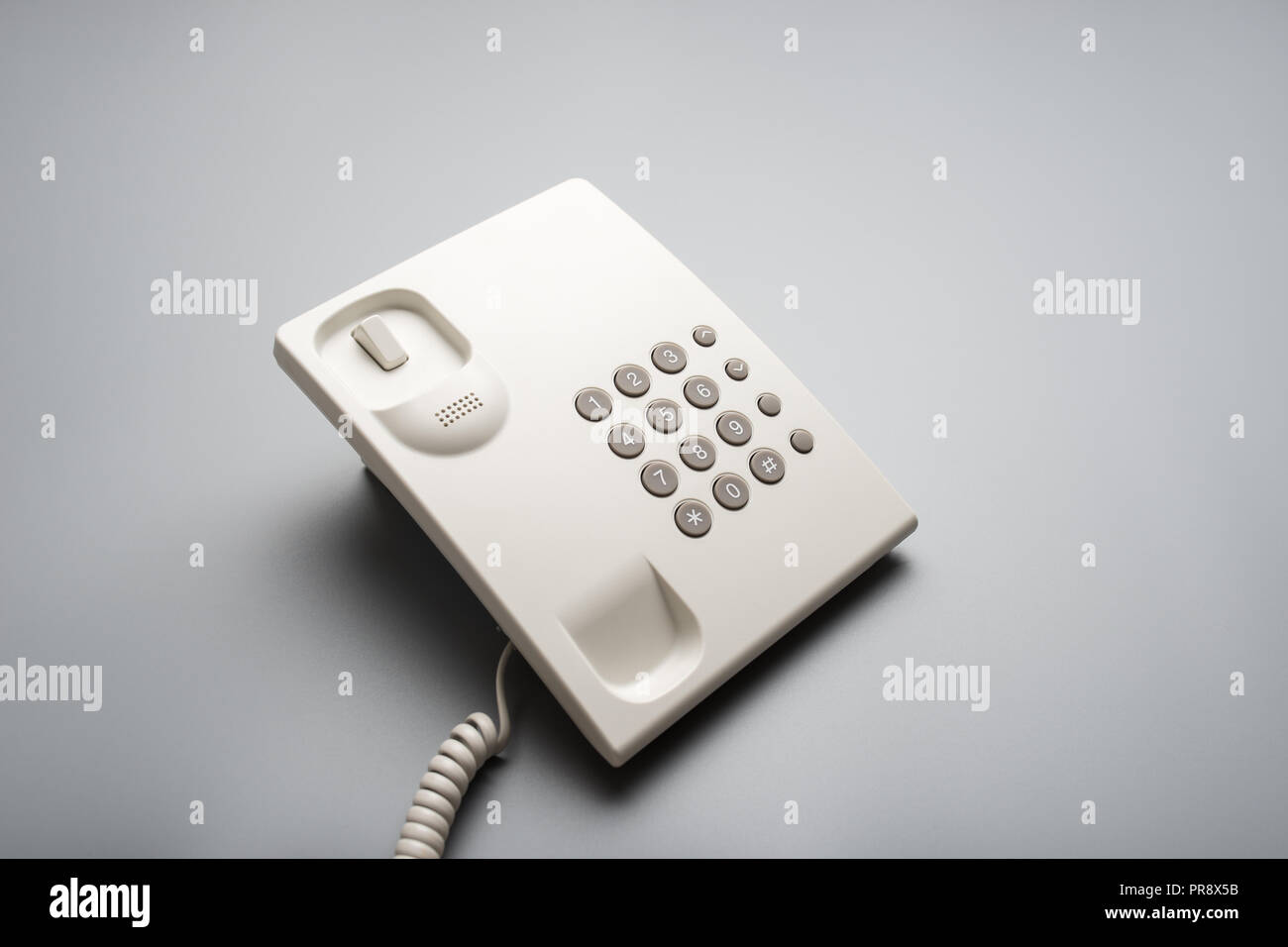 White landline telephone on grey background Stock Photo - Alamy