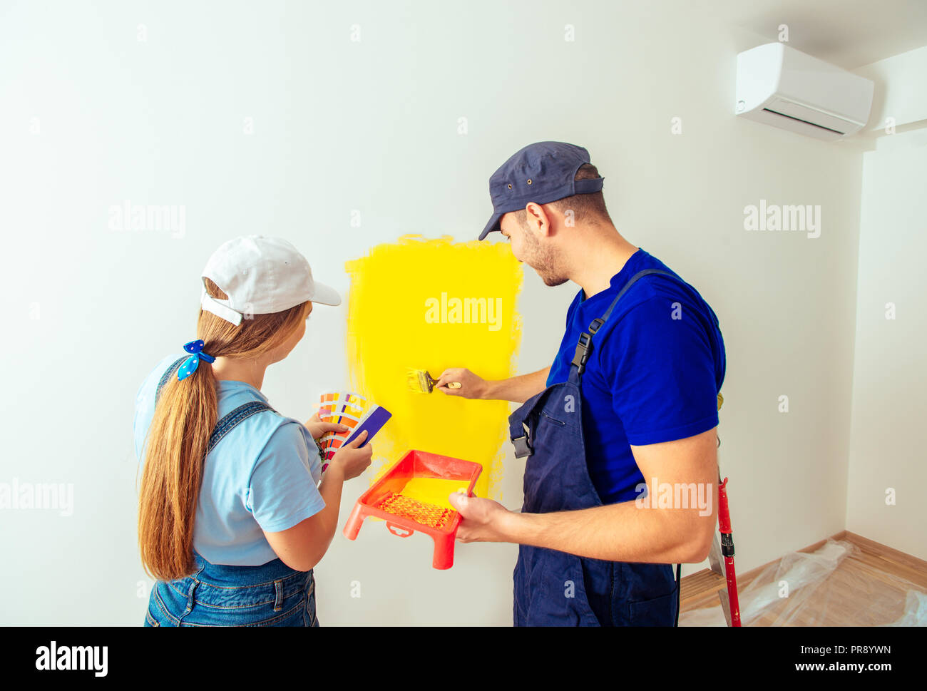 Adorable married couple doing home makeover with yellow color Stock ...