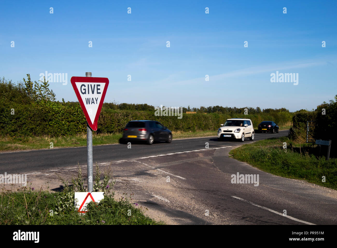 give way road sign on country lane joining main highway junction in ...