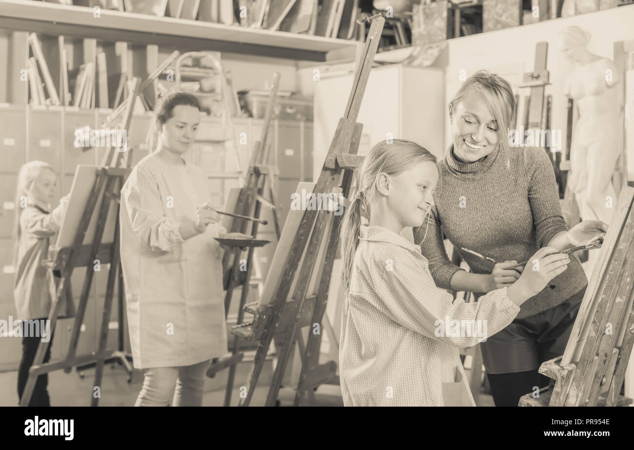 Happy female teacher assisting student during painting class at art ...