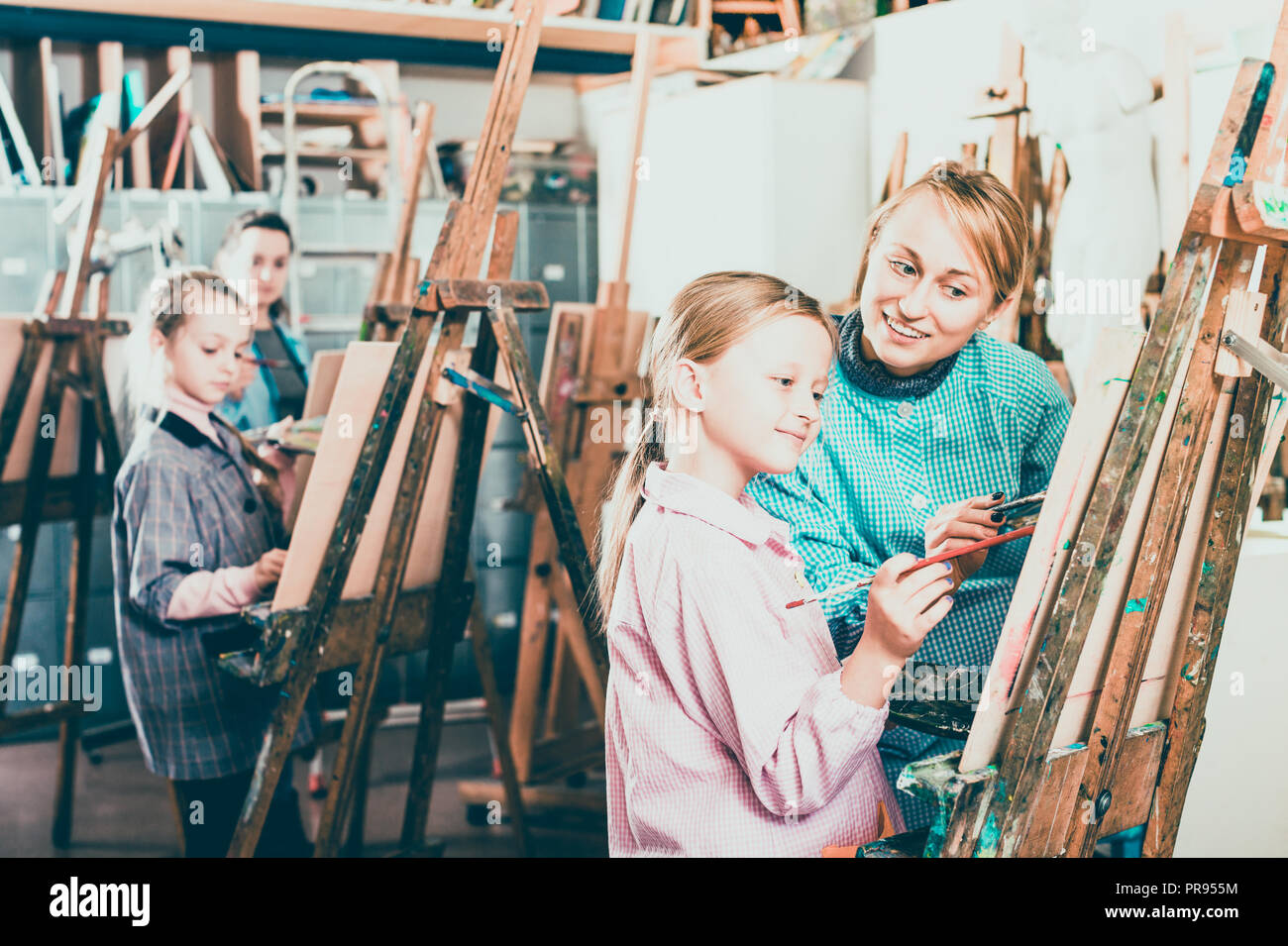 Portrait female teacher helping girl during painting class at art ...