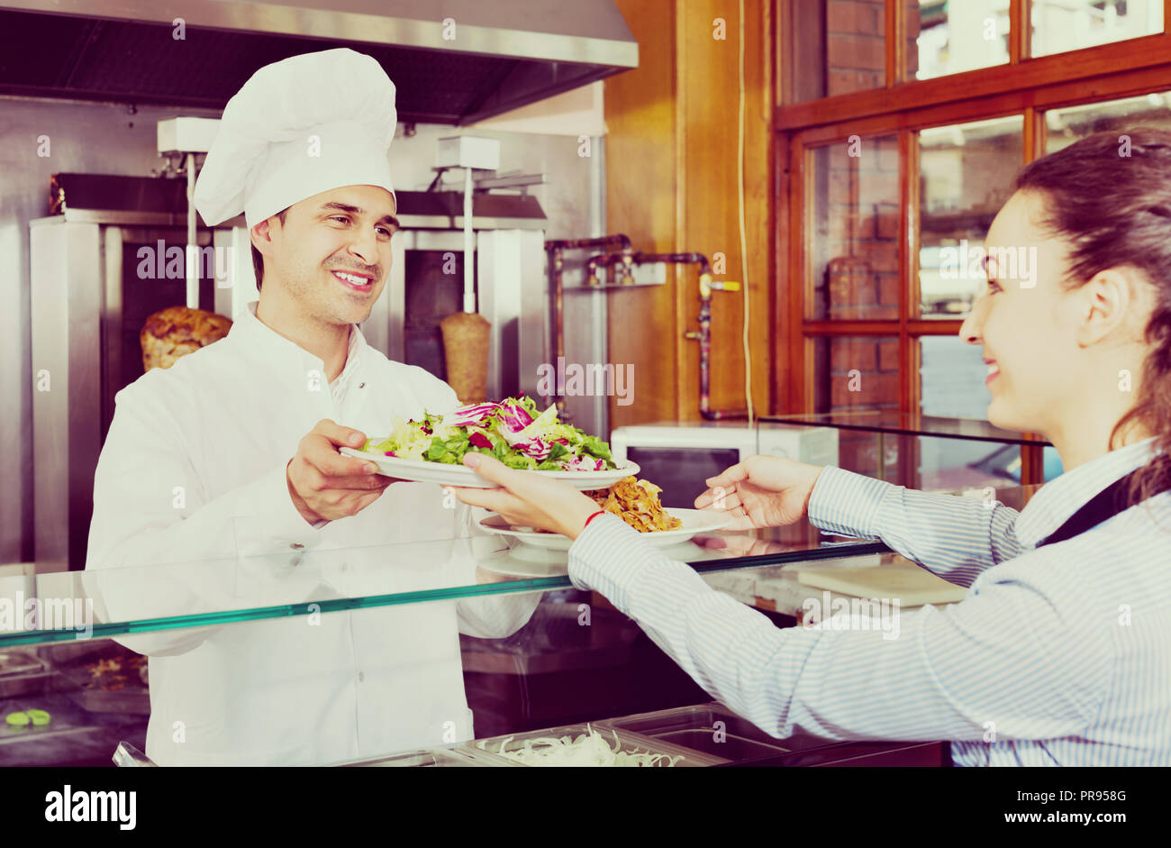 Happy professional chef and young waitress taking kebab for client ...