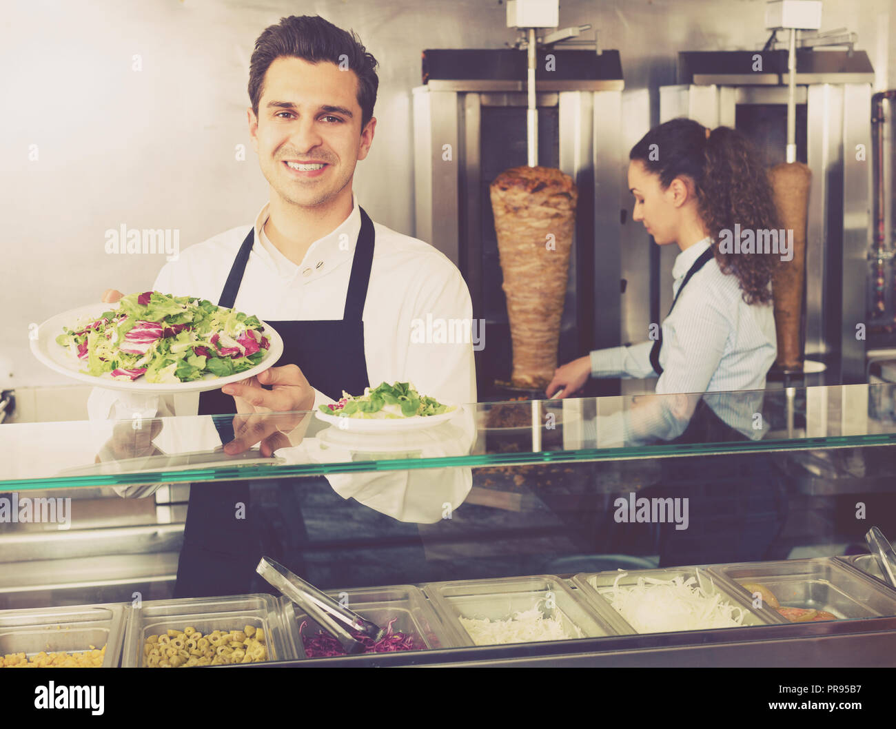 Portrait of two young workers with kebab at fastfood place Stock Photo ...