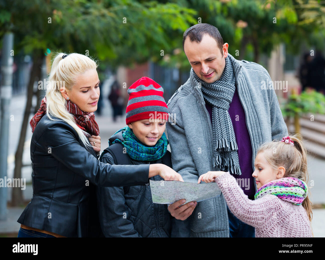 Happy middle class family of four checking direction in city map Stock ...