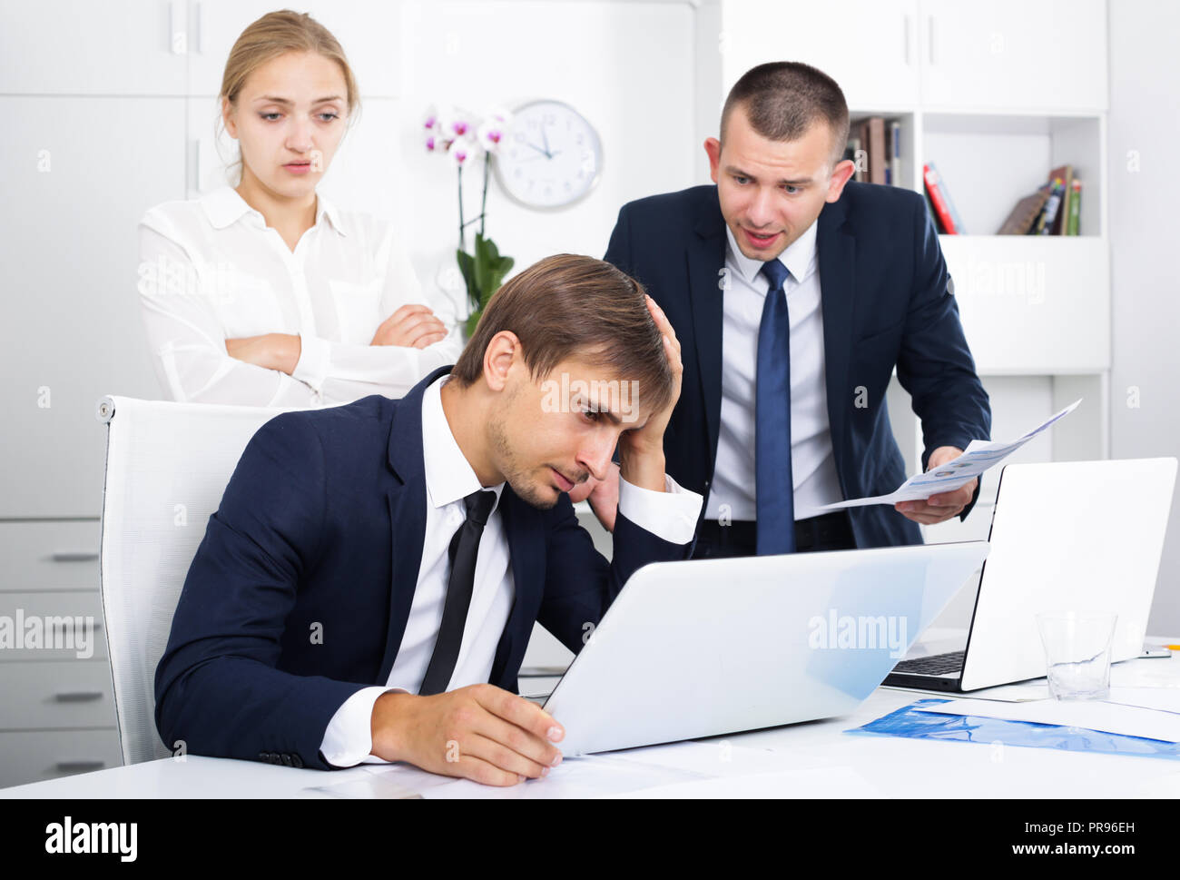 three concerned business assistants making mistake in company office ...