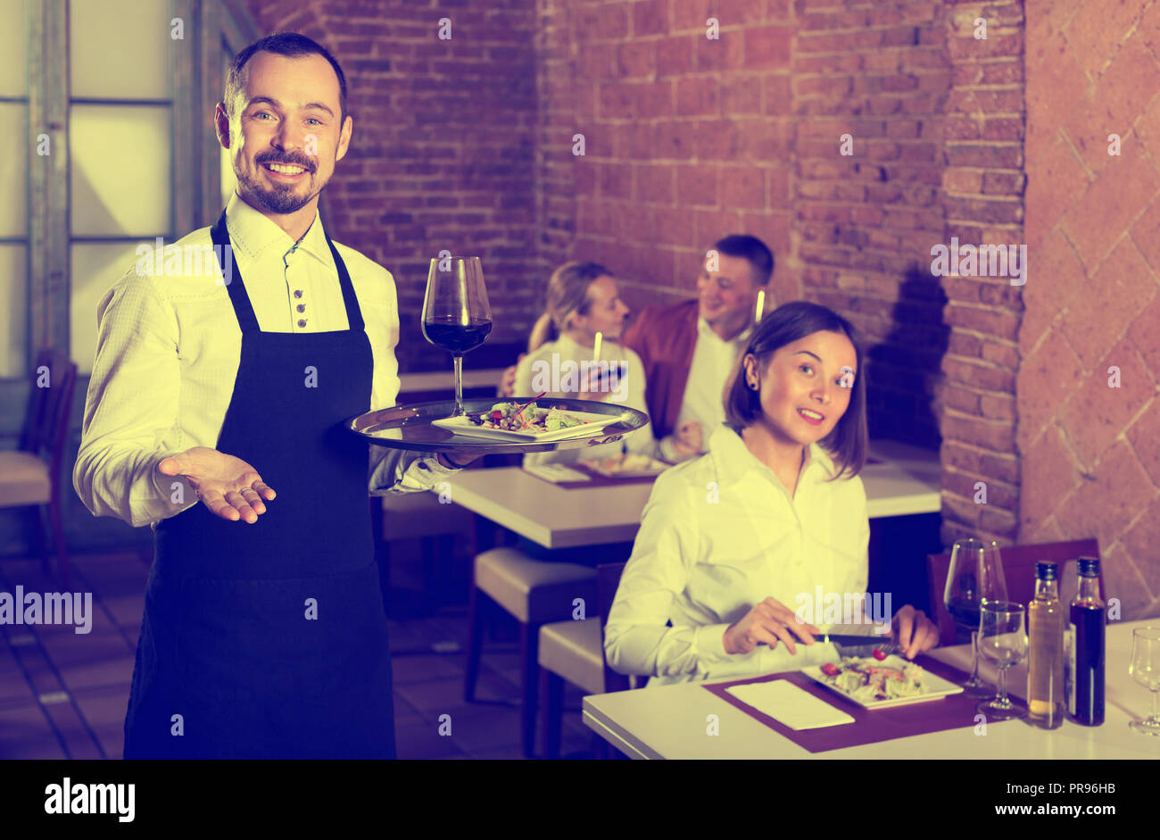 Cheerful male waiter showing country restaurant to visitors Stock Photo ...