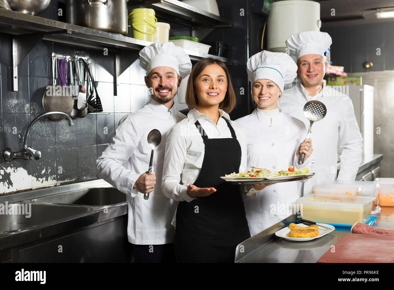 Pretty female waiter taking ordered dishes from restaurant’s kitchen ...