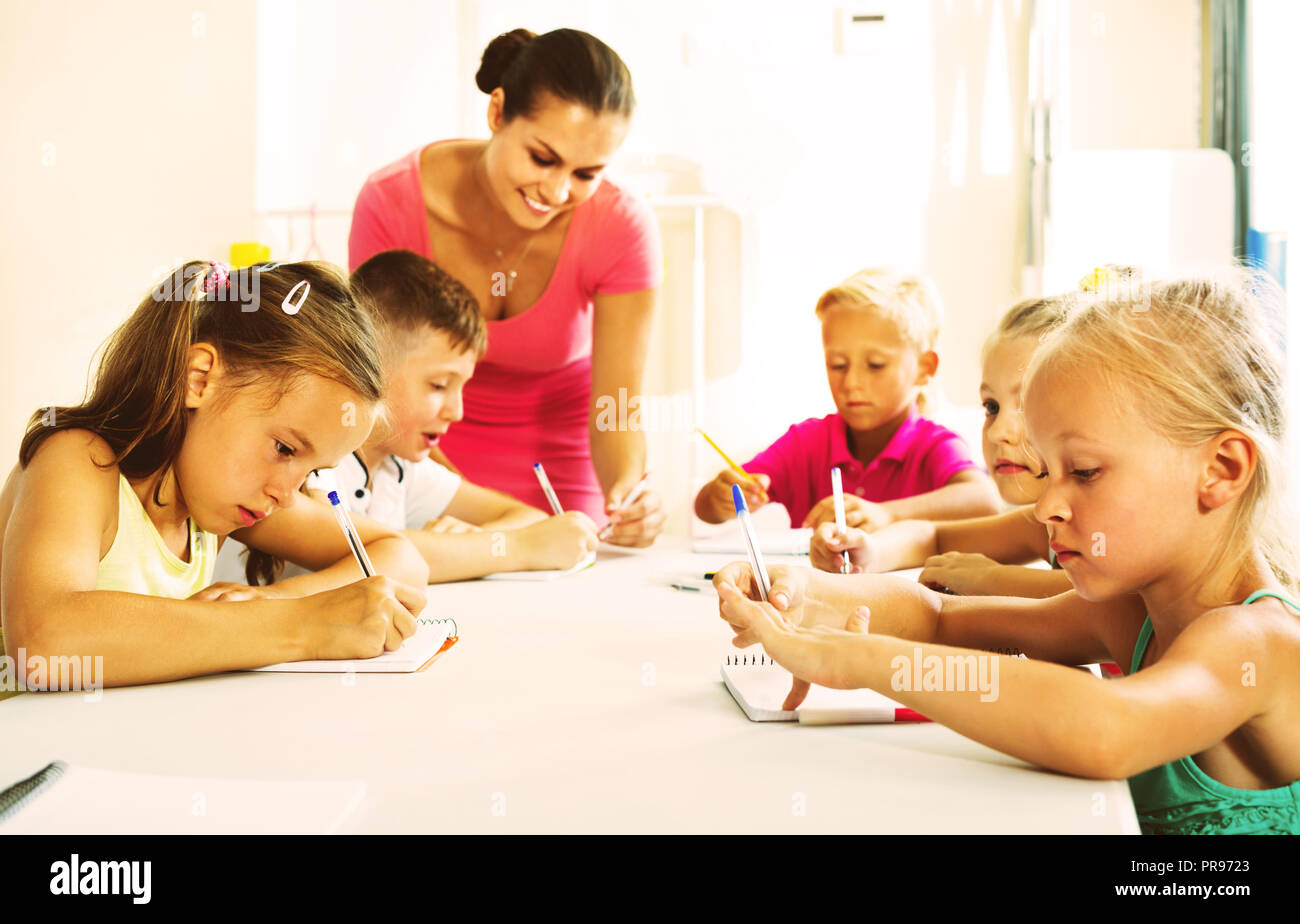Smiling diligent kids learning to write on lesson in elementary school ...