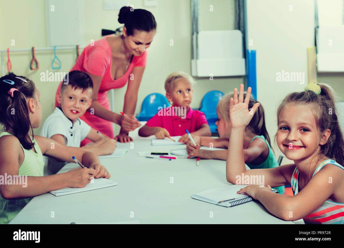 Cheerful diligent kids learning to write on lesson in elementary school ...