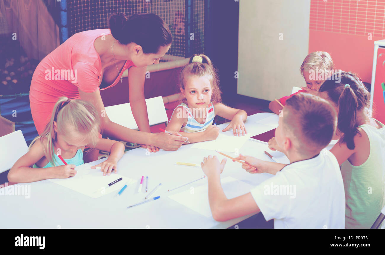 Glad kids drawing on lesson in elementary school class with help of ...