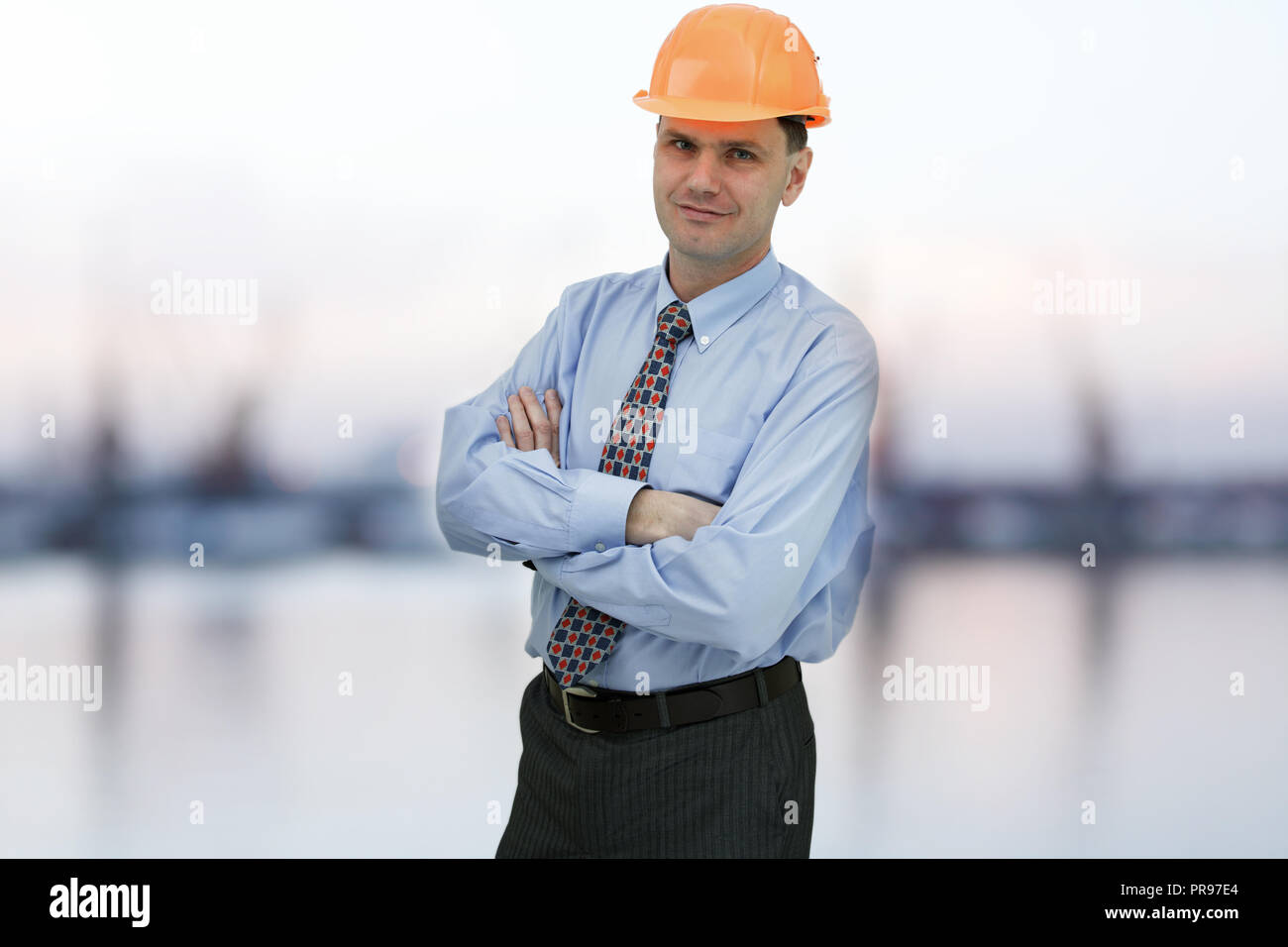 Engineer with crossed arms in a hard hat against a port Stock Photo - Alamy