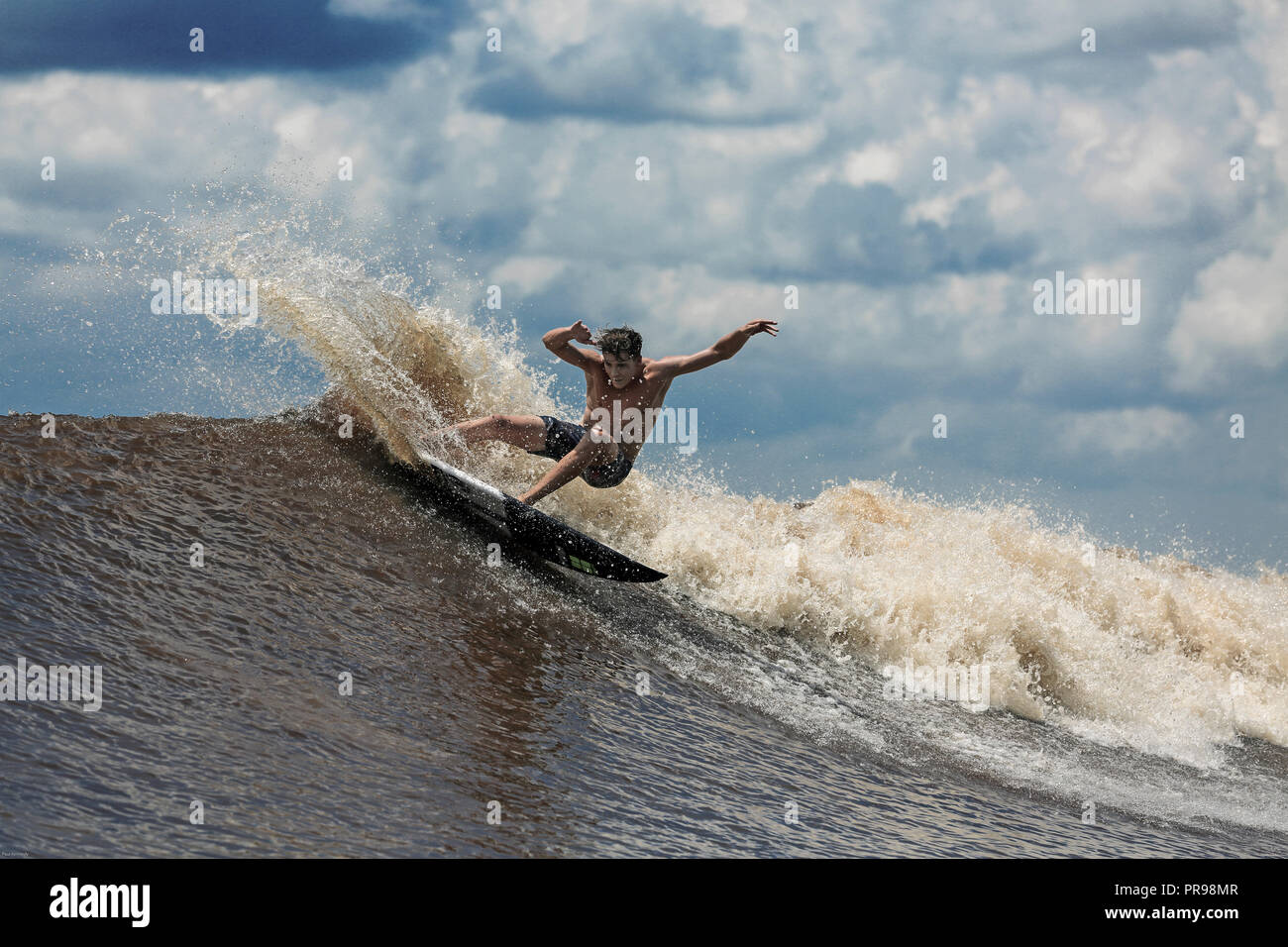 Surfer surfing river bore wave on the Kampar River in Sumatra ...